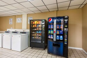 Uma lavanderia com máquina de vendas de Pepsi, uma secadora e uma máquina de lavar.