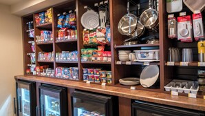 Uma cozinha com prateleiras repletas de alimentos, panelas, utensílios e acessórios de cozinha.