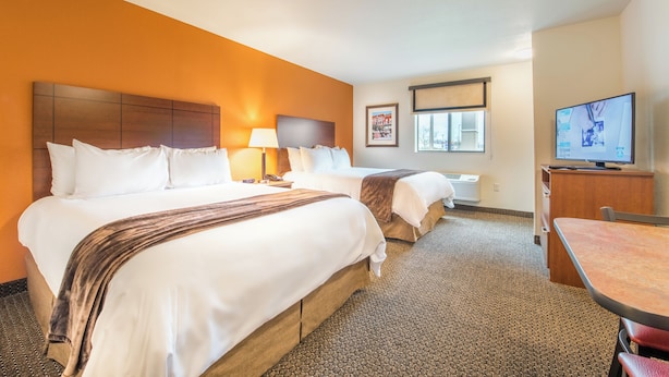 Quarto de hotel com duas camas, televisão, escrivaninha e janela.