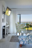 Uma sala de estar moderna com lareira, um sofá, uma mesa de centro e vista para o mar.
