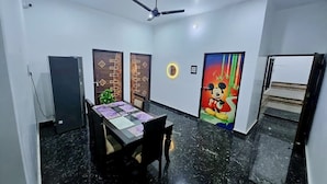 Uma sala de conferências com piso de mármore preto, um ventilador de teto, uma mesa com cadeiras e um quadro colorido do Mickey Mouse na parede.