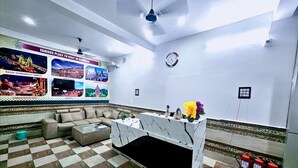 Um saguão com piso xadrez, um sofá, um balcão de recepção de mármore e uma parede com cartazes.