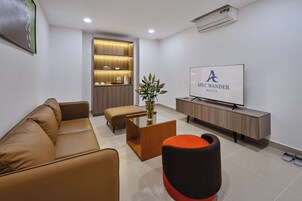 Uma sala de estar moderna com sofá, apoio de pés, mesa de centro e televisão de tela plana.