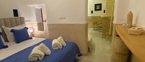Quarto de hotel com cama, escrivaninha, cadeira, aparelho de ar condicionado e piso estampado.