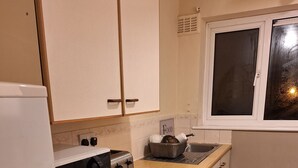 Uma cozinha compacta com micro-ondas, torradeira, pia e máquina de lavar.