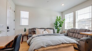 Quarto moderno com uma cama grande, um sofá, uma mesa de jantar e um vaso de plantas.