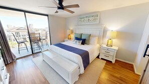 Quarto com cama, mesas de cabeceira, ventilador de teto e vista para o exterior.