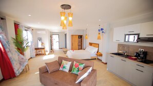 Quarto de hotel moderno com cama, sofá, cozinha e área de jantar.