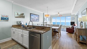 Cozinha moderna com bancadas de granito, eletrodomésticos de aço inoxidável e vista para o oceano.