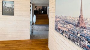 Um interior moderno com paredes de madeira, um grande mural da paisagem urbana e uma escadaria que leva a outro cômodo.