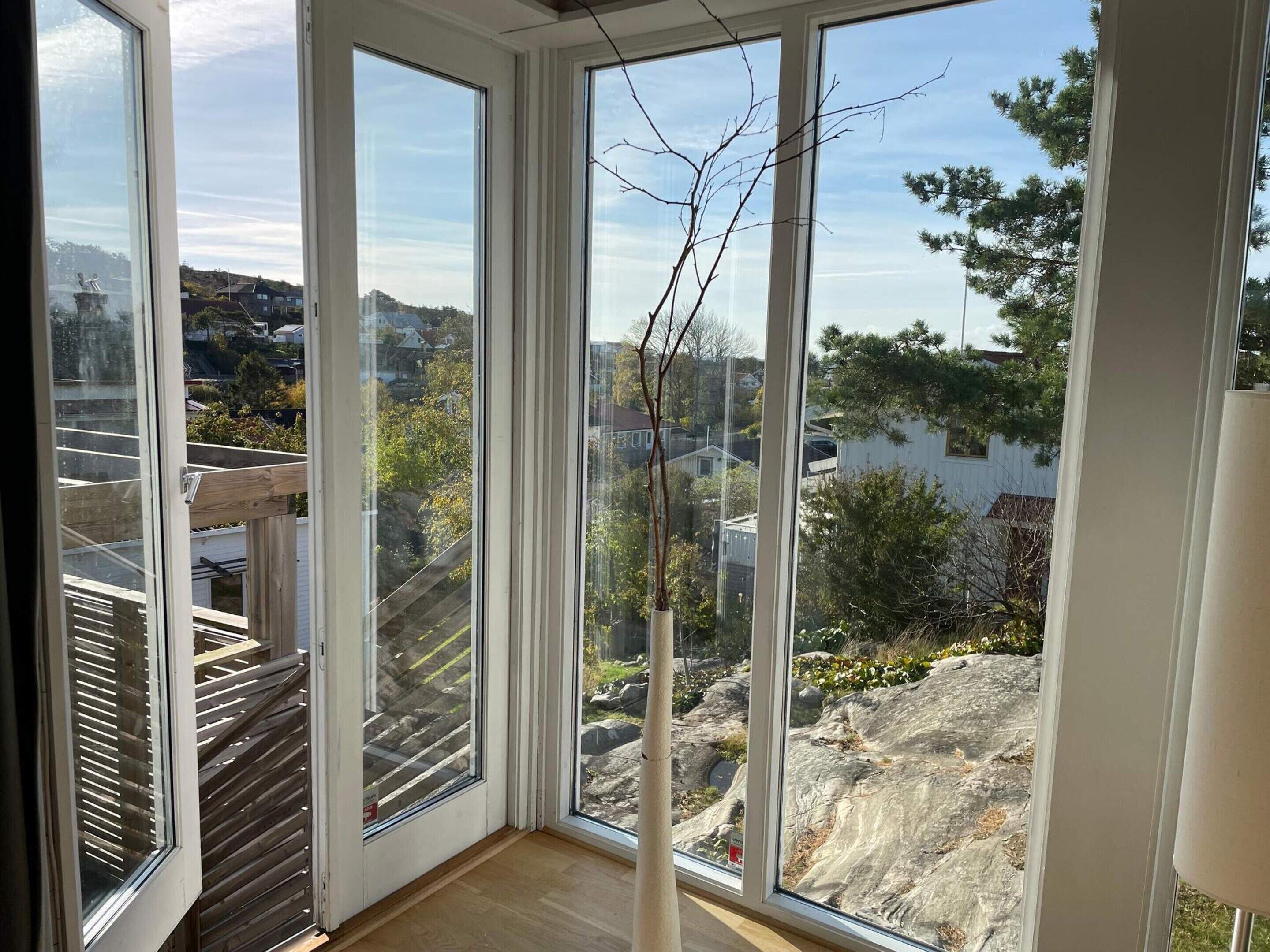 Quarto com grandes janelas oferecendo vista para uma área residencial e um corpo d'água.