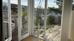 Quarto com grandes janelas oferecendo vista para uma área residencial e um corpo d'água.