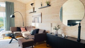 Uma sala de estar moderna com sofá, apoio de pés, mesa de centro e aparador com objetos decorativos.
