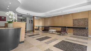 Uma área de recepção moderna com um balcão curvo, espaço de estar e azulejos decorativos.