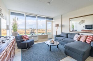 Uma sala de estar moderna com uma janela ampla, um sofá, uma mesa de centro e uma televisão.