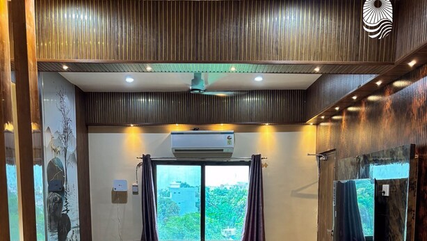 Sala de estar moderna com sofá, banquinho e televisão de tela plana fixada numa parede de madeira.