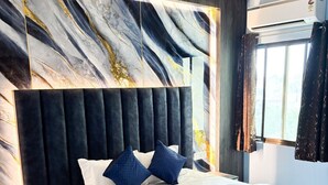 Quarto moderno com uma cama grande, cabeceira com design que lembra mármore e janela com cortinas.