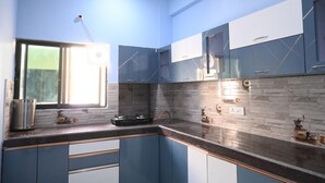 Uma cozinha moderna com armários azuis, uma janela e painel de azulejos.