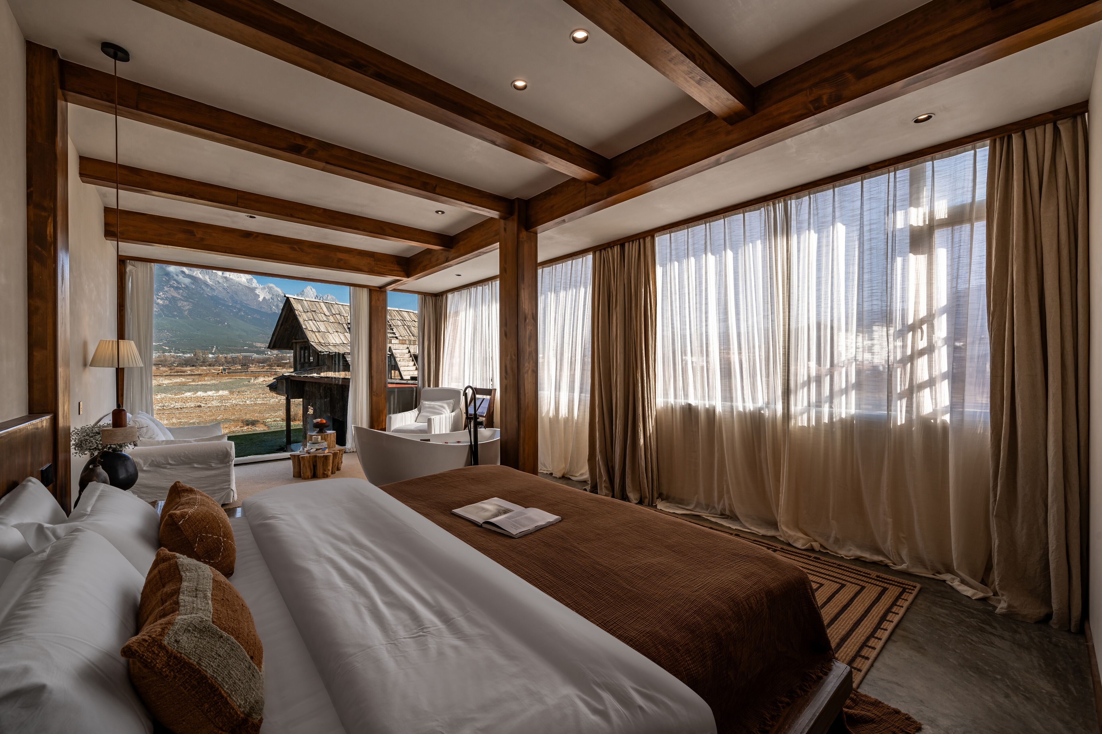 Quarto de hotel com uma cama grande, uma escrivaninha e vista para montanhas.
