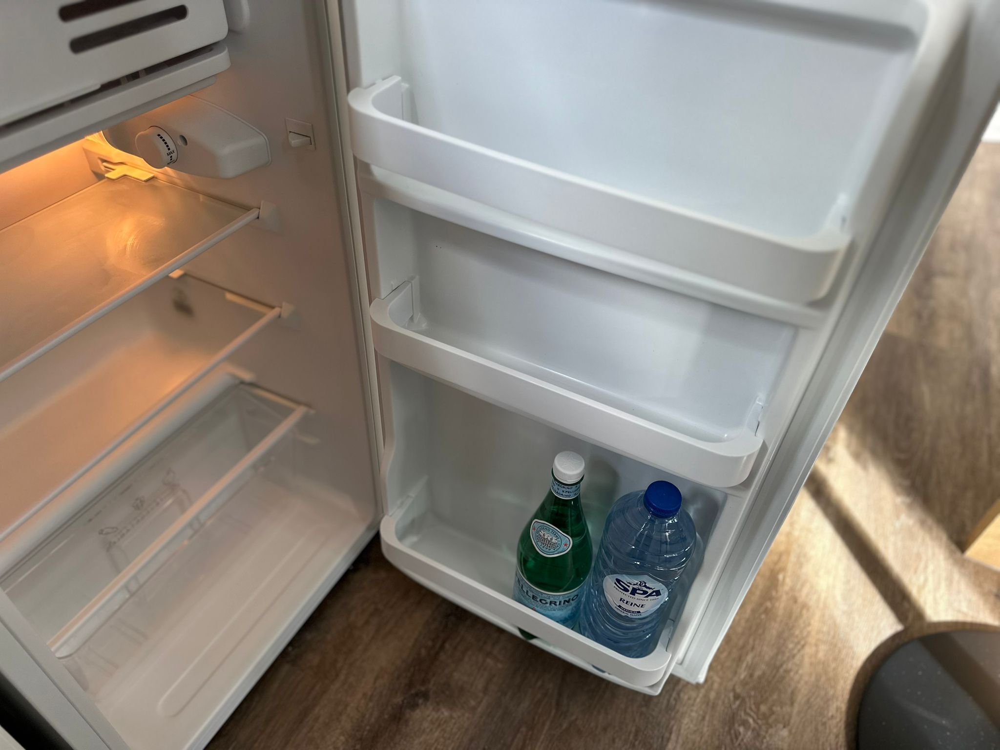 Geladeira aberta com duas garrafas de água na prateleira inferior.