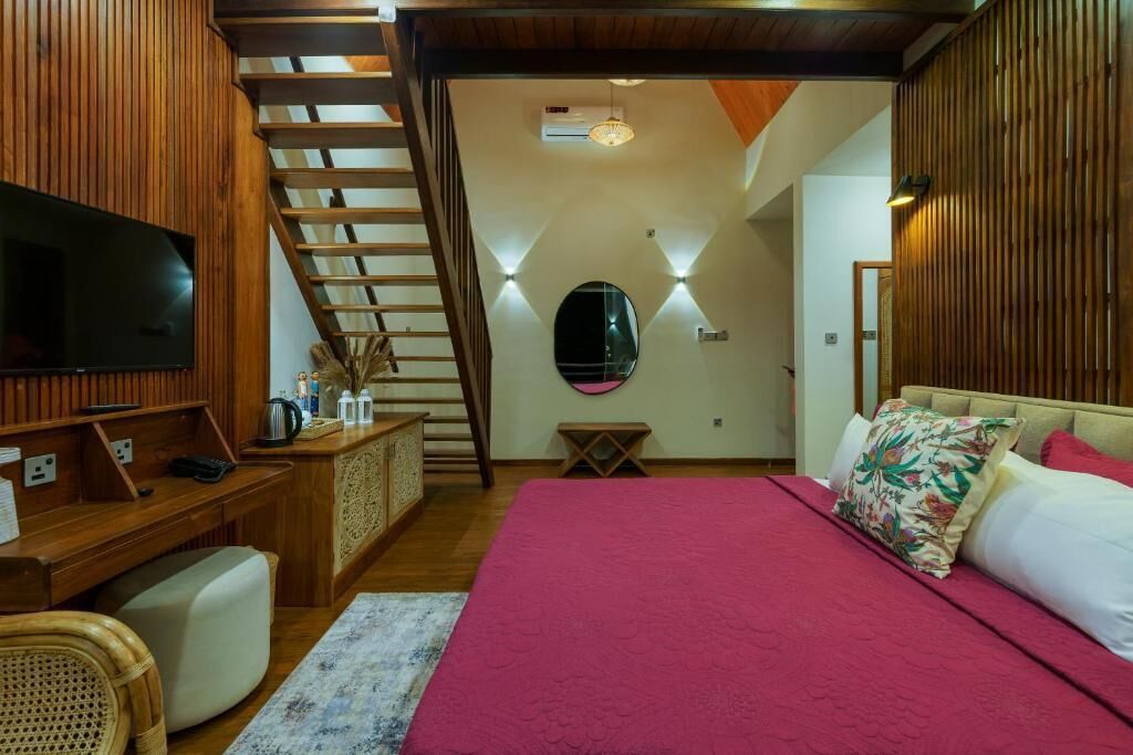 Quarto com cama grande, móveis de madeira, televisão e escada.