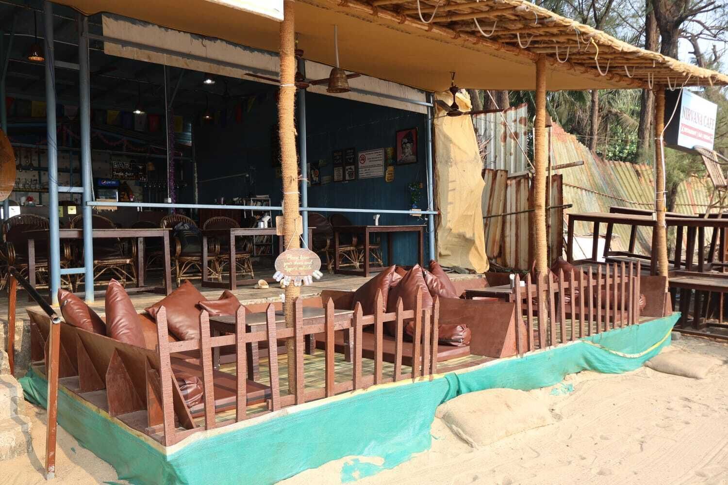 Um restaurante à beira-mar com mesas ao ar livre, área coberta e vista para o mar.