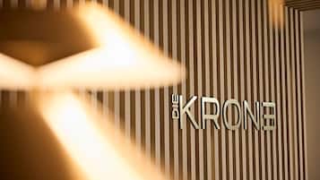 Pared com ripas verticais de madeira e o texto 'THE KRONE' numa fonte metálica.