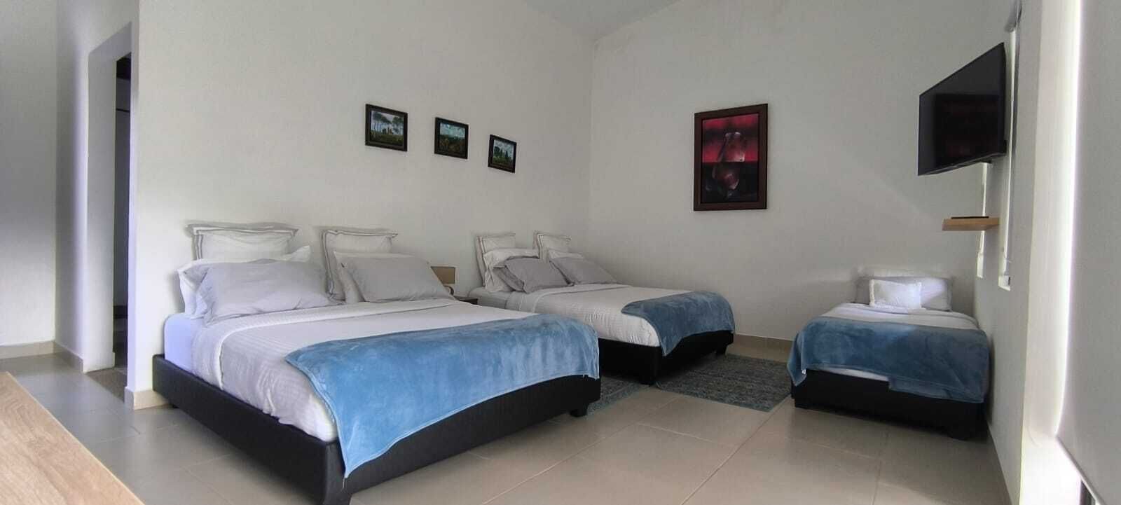 Quarto de hotel com duas camas, uma TV de tela plana e três quadros na parede.
