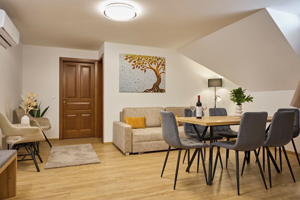 Uma sala de estar moderna com sofá, mesa de jantar, cadeiras e piso de madeira.