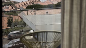 Vista de varanda sobre uma cidade costeira com casas em terraços e o mar ao longe.