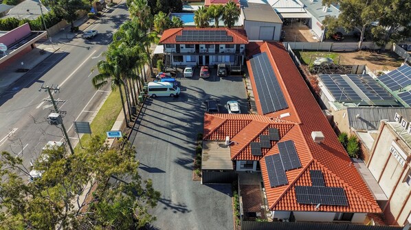 Um edifício com telhado de telhas vermelhas, painéis solares e uma placa indicando um motel.