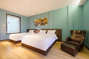Quarto de hotel com duas camas, uma poltrona de couro marrom e uma janela grande.