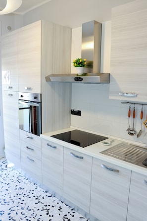 Cozinha moderna com forno embutido, exaustor de aço inoxidável e uma pia com tábua de corte.