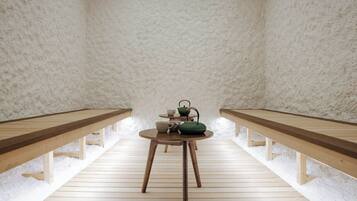 Uma sala de sauna com bancos de madeira e uma mesa central com chaleira e xícaras.