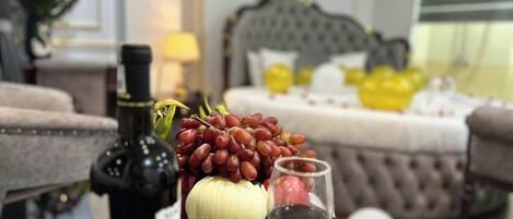 Uma mesa de jantar com uma garrafa de vinho, uma tigela de uvas, uma cebola fatiada e um copo de vinho tinto.