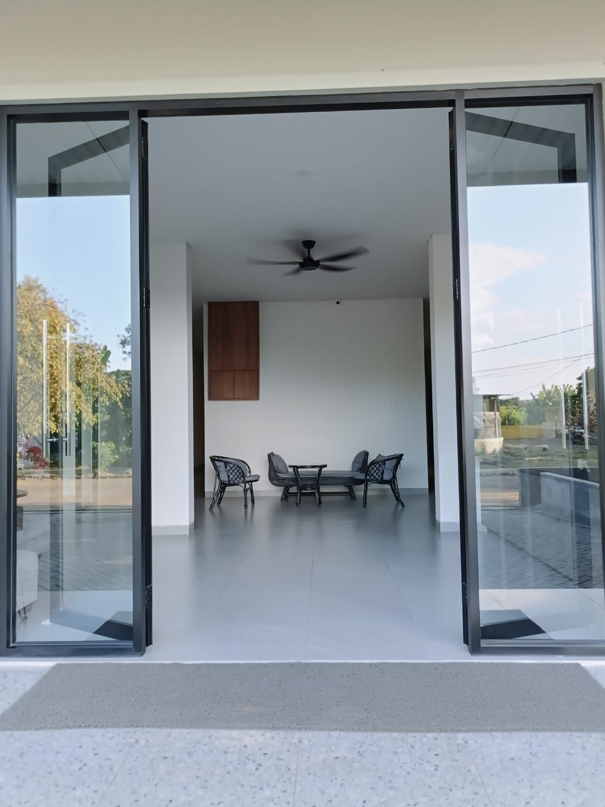 Quarto moderno com porta de vidro para área externa, ventilador de teto e espaço para sentar.