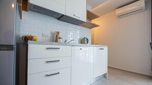 Uma cozinha moderna com armários brancos, uma geladeira de aço inoxidável e um forno embutido.