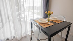 Uma mesa de jantar com duas tigelas brancas, uma colher e um vaso com flores amarelas.