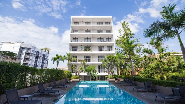 Um edifício moderno de vários andares com piscina e espreguiçadeiras.