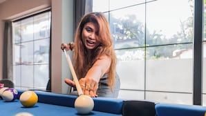 Uma mesa de bilhar com bolas e uma pessoa jogando.