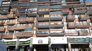 Um edifício com vários andares, varandas e lojas no térreo.