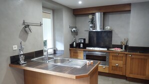 Uma cozinha moderna com ilha central, eletrodomésticos de aço inoxidável, armários de madeira e forno embutido.
