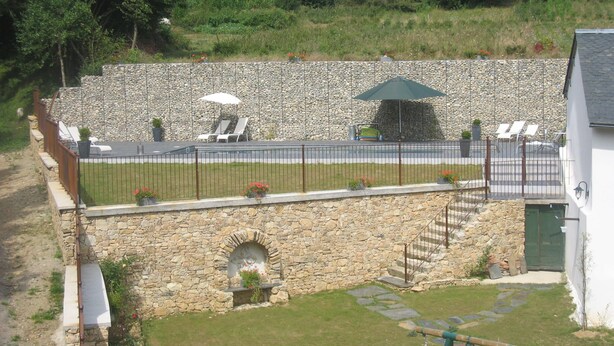 Um muro de pedra com uma escadaria de pedra que leva a uma porta, um banco de pedra e um muro de pedra com um arco.