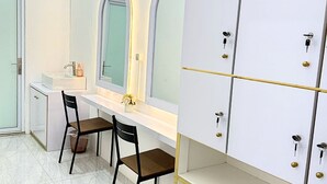 Casa de banho com toucador branco, duas espelhas, lavatório e aparador com várias gavetas.