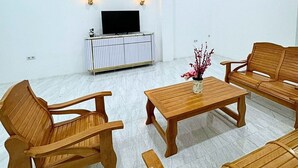 Uma sala de estar moderna com móveis de madeira, uma TV de tela plana e arandelas decorativas.