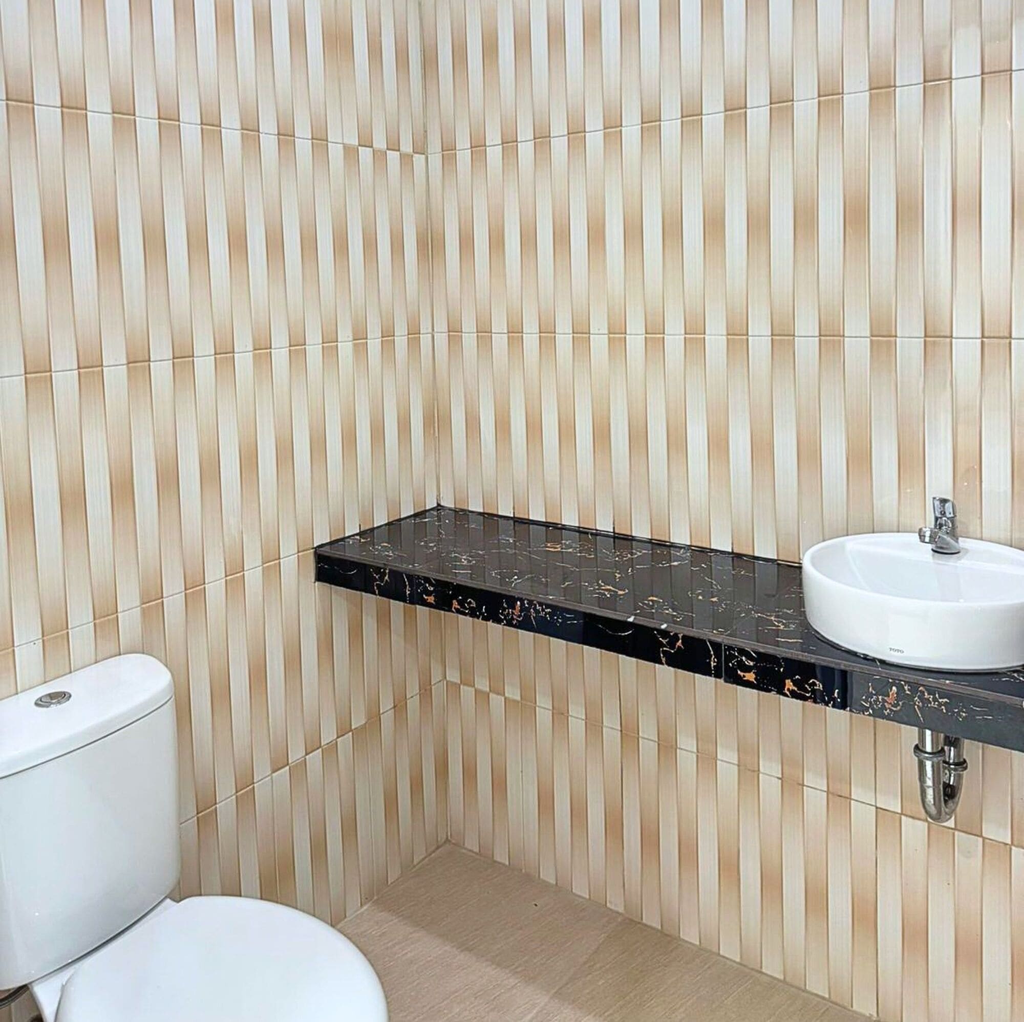 Casa de banho com sanita, lavatório e parede com padrão vertical riscado.