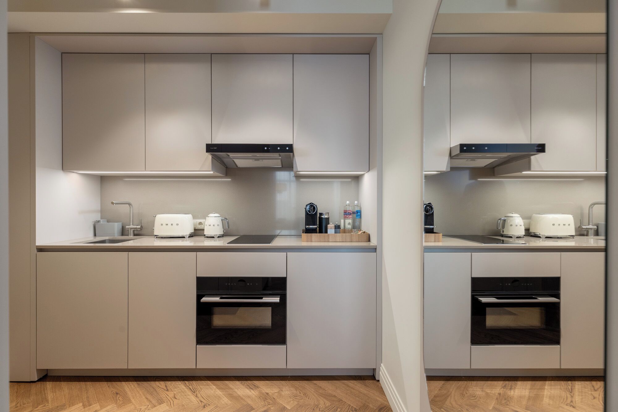 Uma cozinha moderna com dois fornos, um balcão com eletrodomésticos e piso de madeira.