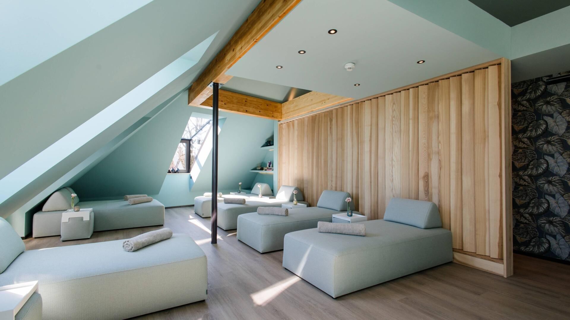 Quarto de loft moderno com teto inclinado, painéis de madeira embutidos e uma grande janela que permite entrada de luz natural.