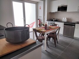 Uma cozinha moderna com uma panela grande no balcão, uma mesa de jantar com cadeiras, micro-ondas e máquina de lavar louça.