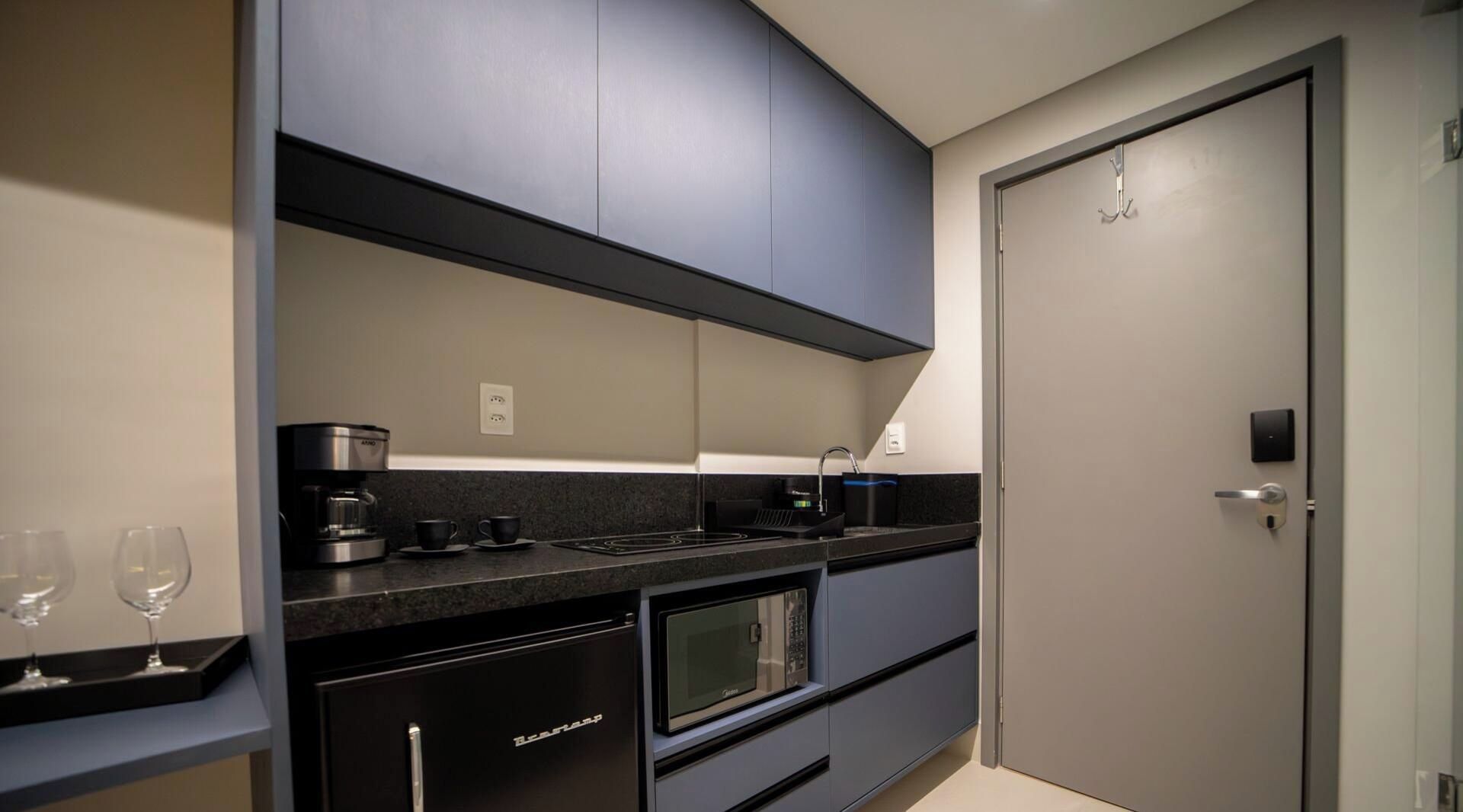 Cozinha moderna com cafeteira, micro-ondas e armários.